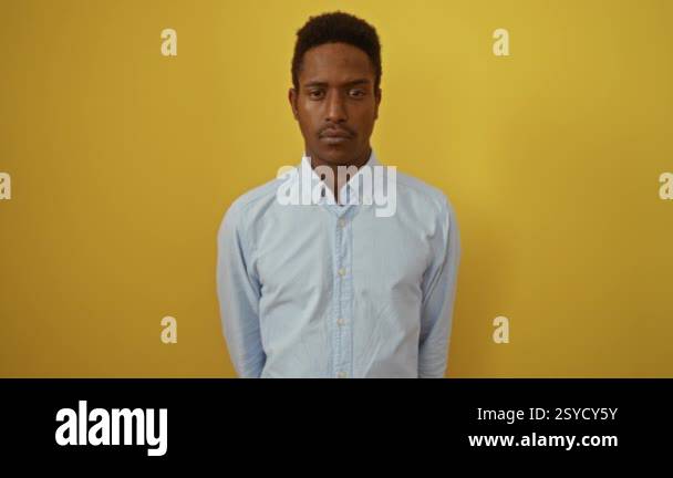 Young african american man, person wearing shirt, standing frowning ...