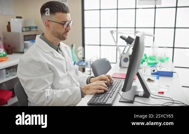 Handsome hispanic scientist in lab coat working on computer in modern ...