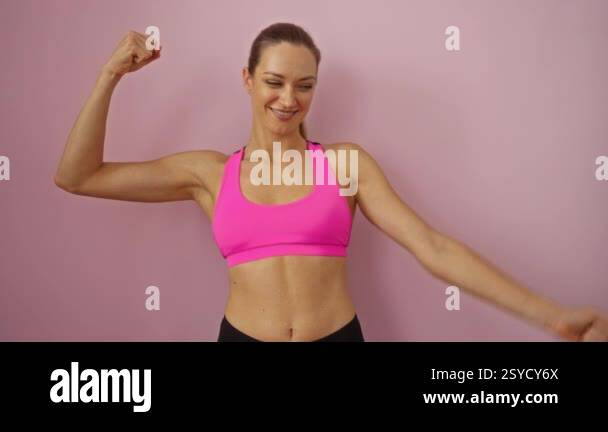 Woman flexing arms confidently against an isolated pink background ...