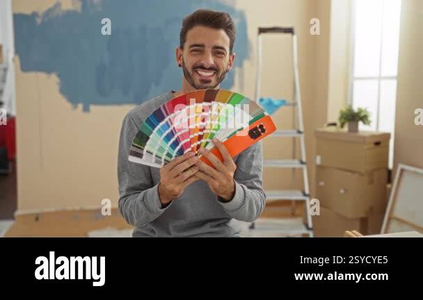 Young man choosing paint colors for home renovation in a bright living ...