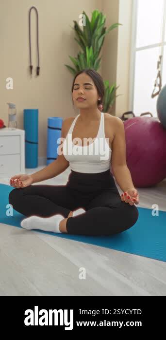 Woman meditating on yoga mat indoors, emphasizing calm and relaxation ...