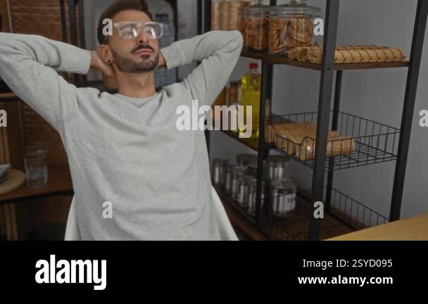 Young man relaxing in an office with shelves in the background ...