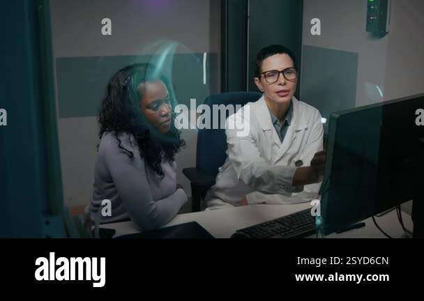 Medium shot, from behind glass window with MRI machine reflection, of ...