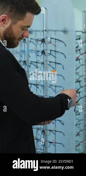 Man trying new eyeglasses. Young man checking new glasses at optician ...