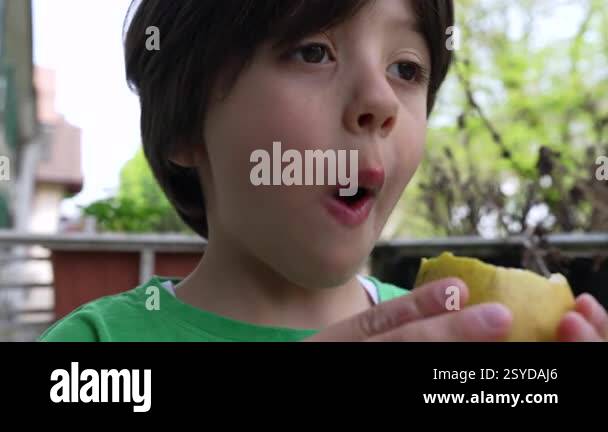 Young child taking a big bite of a pear outside, highlighting natural ...