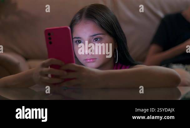 Young girl lying on table fixated on smartphone, signs of social media ...