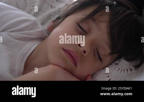Close-up of a child sleeping peacefully in bed, capturing the innocence ...