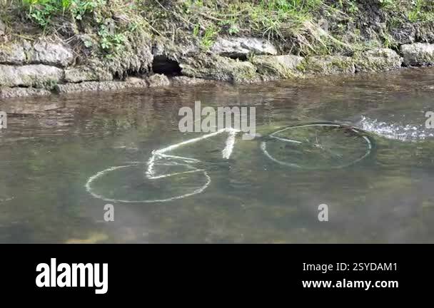 Old bicycle submerged in a shallow stream, clear water revealing the ...