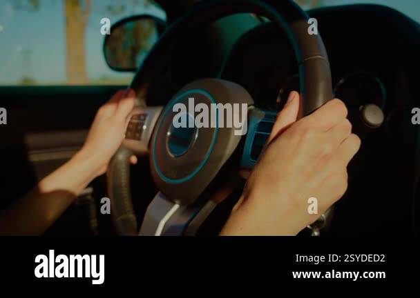 Unrecognizable hands gripping steering wheel driving car through bright ...