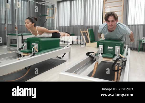 Man and woman practicing back extension exercises on pilates chair to ...