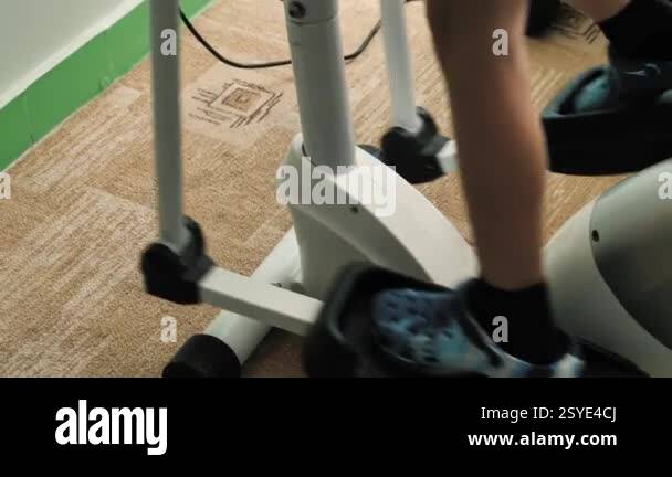 Legs of a boy exercising on a walking machine during physical ...