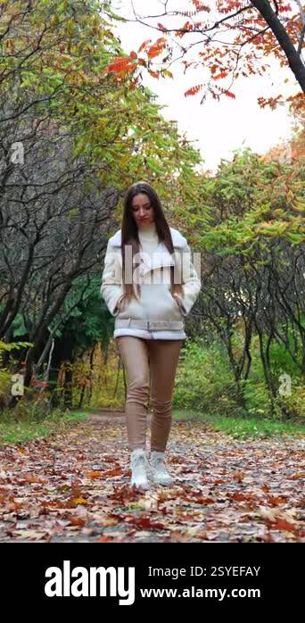 Attractive young woman walking down the park. Pretty lady walking by in ...