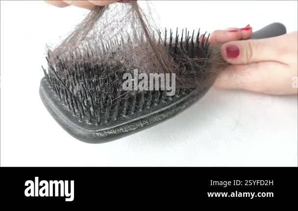 A woman removes her hair from a comb on the table. Hair loss. Hair ...