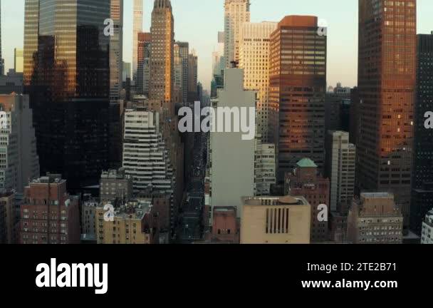 Slider of tall office buildings in city at dusk. Long straight street ...