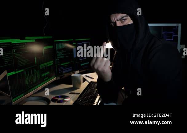 Cyber hacker with hood and covered face looks at the camera showing ...