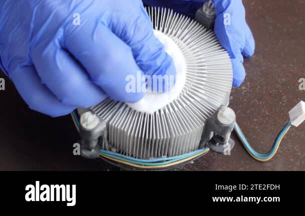 Electronics repair technician carefully cleans the aluminum heatsink for a computer processor on ...