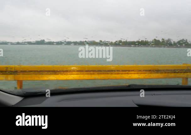 Rain falls on the windshield of a standing car. Wipers wipe raindrops ...