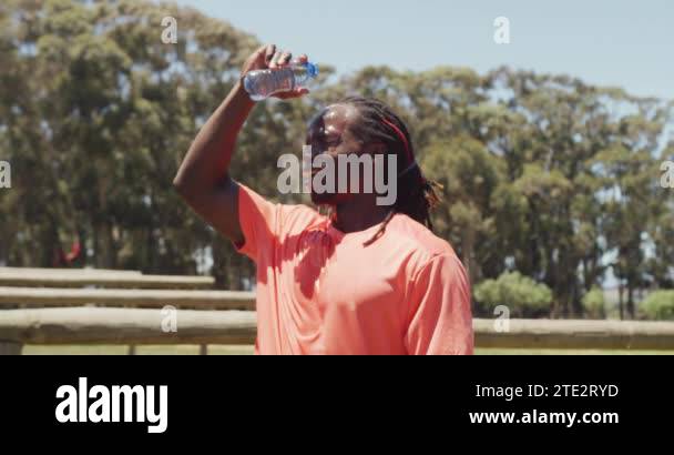 Fit african american man with dreadlocks pouring water over head after ...