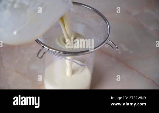 The woman is filtering the pancake dough through sieve to remove the ...
