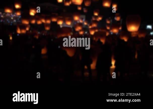 Blurred defocused view of people launching many asian fire lanterns ...