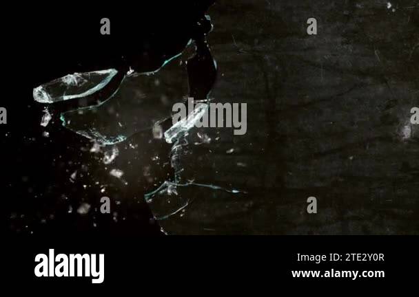 Fragments of broken glass fly in different directions on a black ...