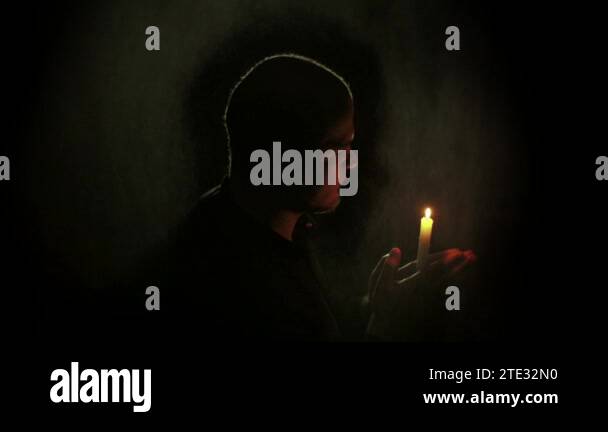 Man blowing out a candle in the dark. Falling water drops. Prayer with ...
