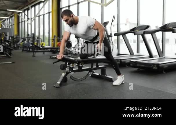 Male athlete doing dumbbell row exercise in gym indoors. Young muscular ...