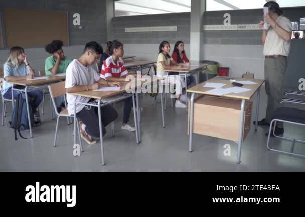 Professor explaining exam exercise in high school classroom to a group ...