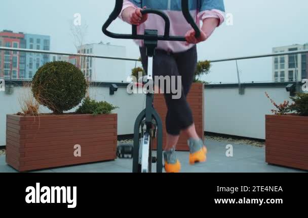 Athletic girl performing aerobic riding training exercises on cycling ...