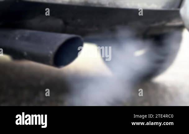 Defocused shot of combustion fumes coming out of car exhaust pipe which ...