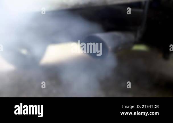 Defocused shot of combustion fumes coming out of car exhaust pipe which ...