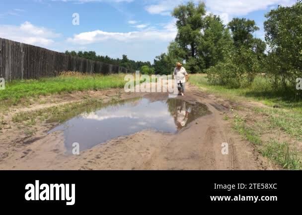 Caucasian senior man with walking stick moving through big puddle on ...