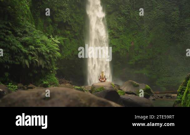 Woman in zen Sukhasana easy pose with mighty water rush from Nungnung ...