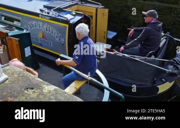 Helmsmen sitting at the stern of two narrowboats navigating Bunbury ...