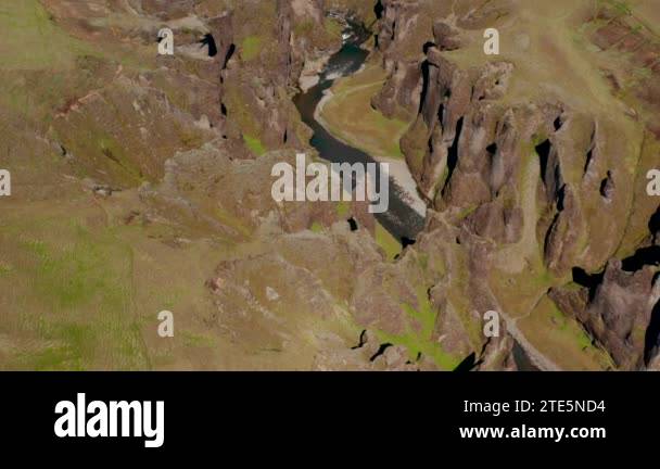 Aerial panoramic footage of ravine cut into ground. Water flowing ...