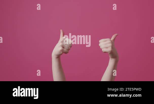 Woman points thumb up against an isolated pink background.Approval hand ...