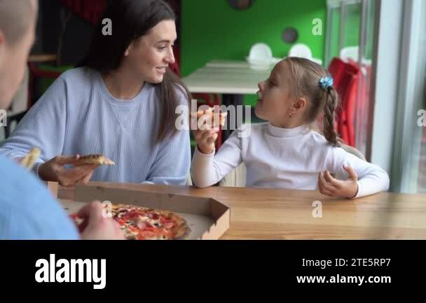 Caucasian family eats pizza in a cafe, delicious dinner in a pizzeria ...