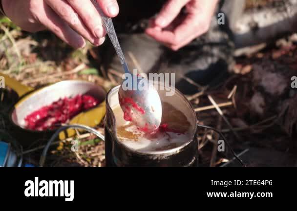 Cooking in a camping pot on a campfire in the forest outdoors. Men's ...