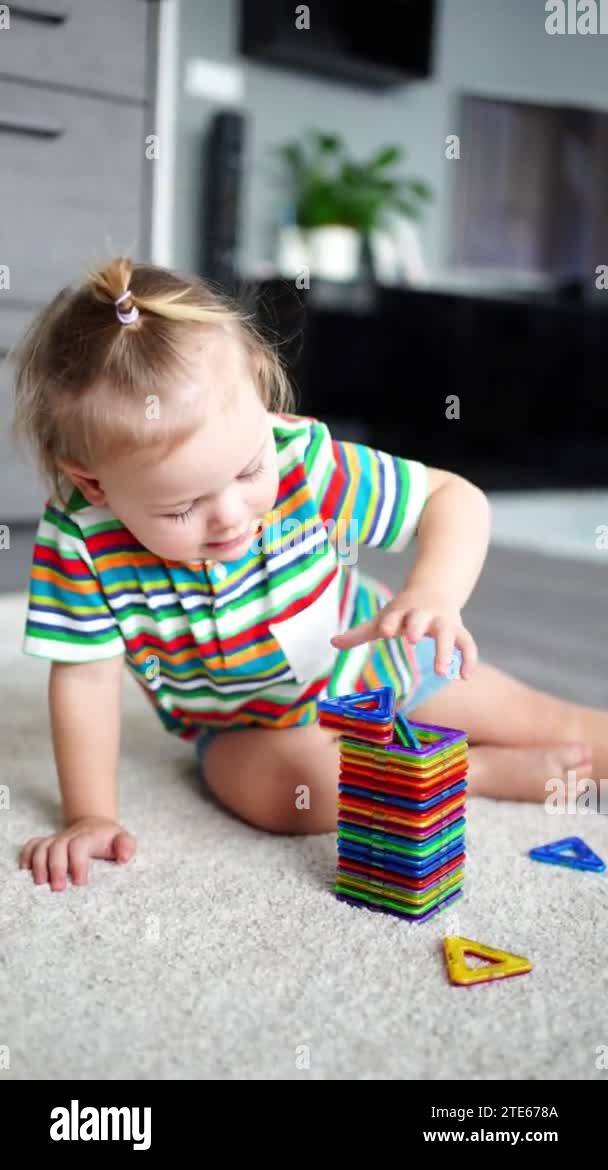 Little girl playing colorful magnet plastic blocks kit at home. The ...