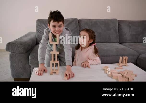 Cheerful Caucasian kids inspecting their wooden block buildings ...