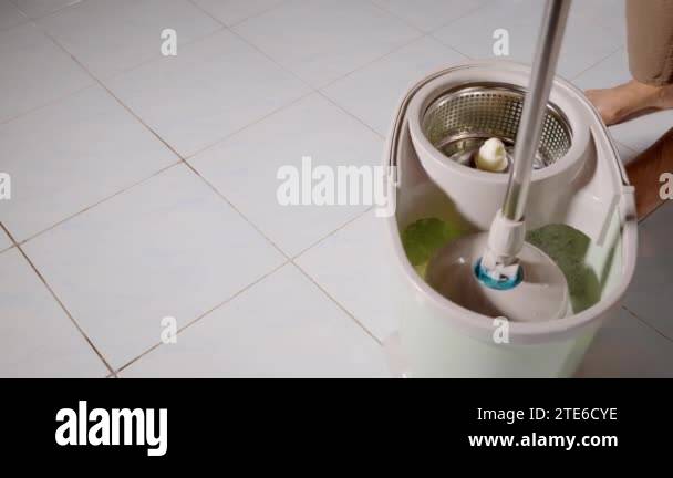 Woman holding mop with microfiber head spinning water in the bucket ...