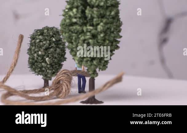 A miniature man tied to a miniature tree and rope. Concept of gender ...