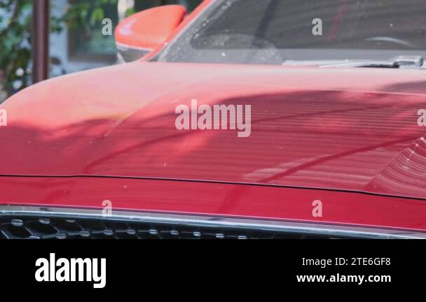 Man pulling car bonnet release lever to open the hood of a modern red ...