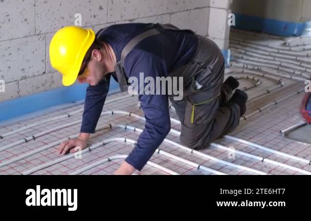A professional plumber install a heated floor. Installation of plumbing ...