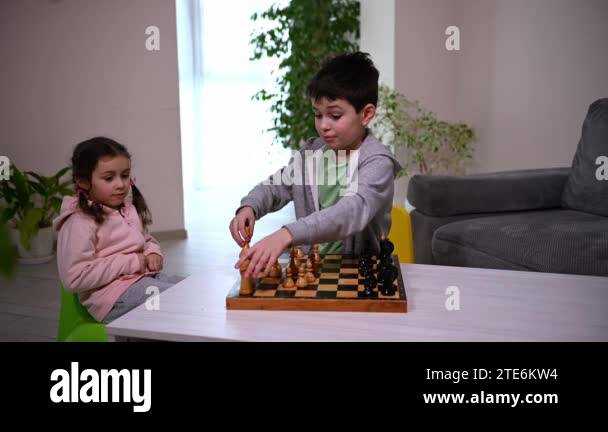 Lovely adorable European children, boy and girl arranging wooden chess ...