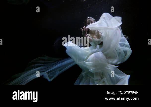 magic mermaid is floating in darkness and depth of ocean, slow motion ...