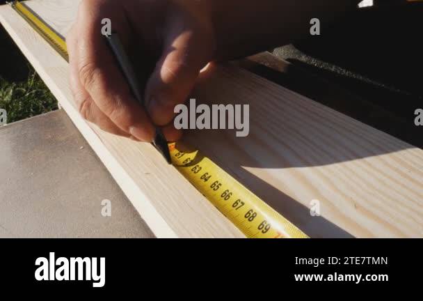 Using a ruler, the worker marks the dimensions with a pencil. Yellow ...