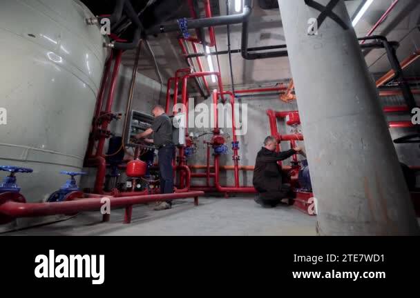 Engineers at the pumping station adjust the hot water supply. Mens ...