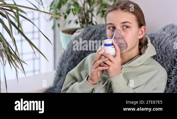 Teenage girl makes inhalation with a nebulizer equipment. Sick child ...