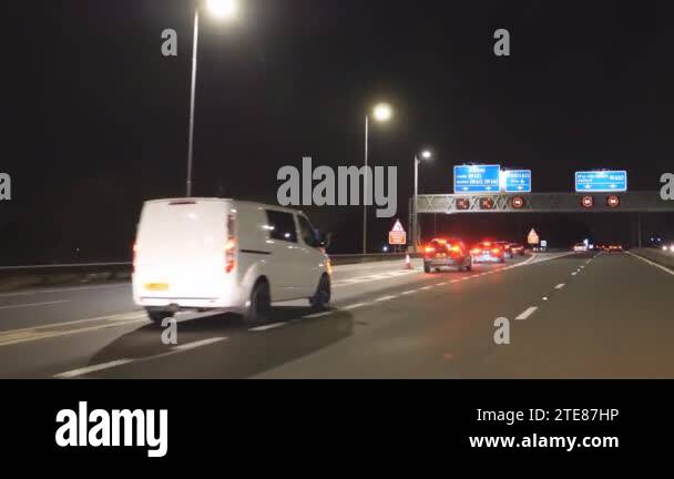 Driving motorway M62 at night at Junction 12. Police cars with blue ...